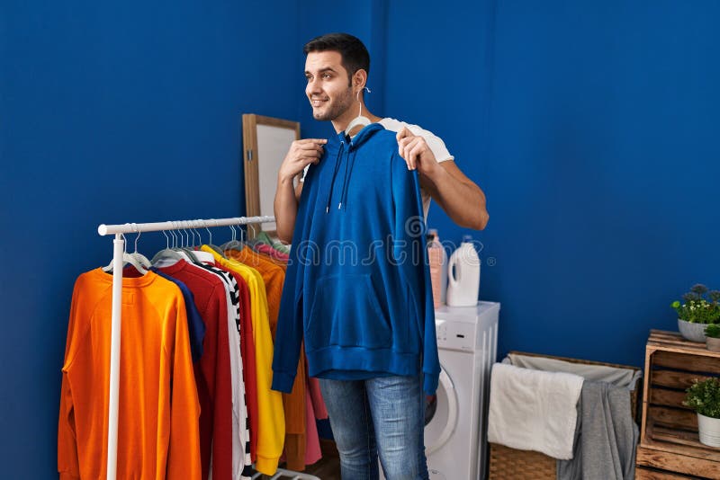 Young Hispanic Man Putting Clothes on Clothes Rack at Laundry Room ...