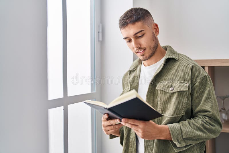 Young Hispanic Man Reading Book Standing at Home Stock Image - Image of ...