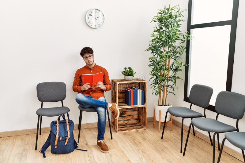 Young Hispanic Man Reading Book at Waiting Room Stock Photo - Image of ...
