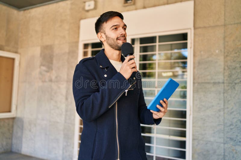 Young Hispanic Man Reporter Working Using Microphone and Touchpad at ...