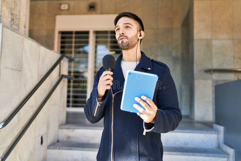 Young Hispanic Man Reporter Working Using Microphone and Touchpad at ...