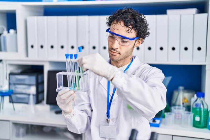 Young Hispanic Man Scientist Holding Test Tubes at Laboratory Stock ...