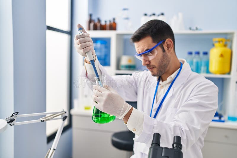 Young Hispanic Man Scientist Measuring Liquid Using Pipette at ...