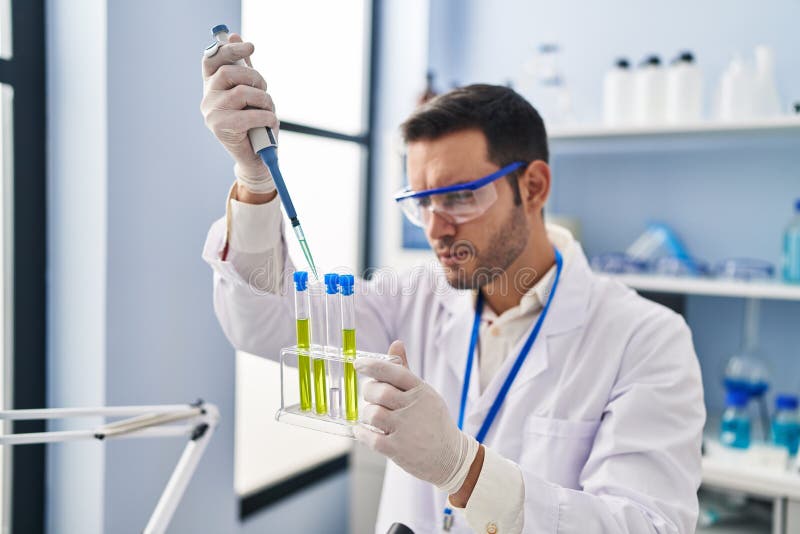 Young Hispanic Man Scientist Measuring Liquid Using Pipette at ...