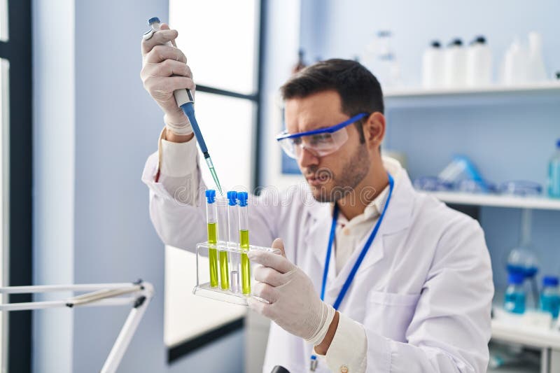 Young Hispanic Man Scientist Measuring Liquid Using Pipette at ...
