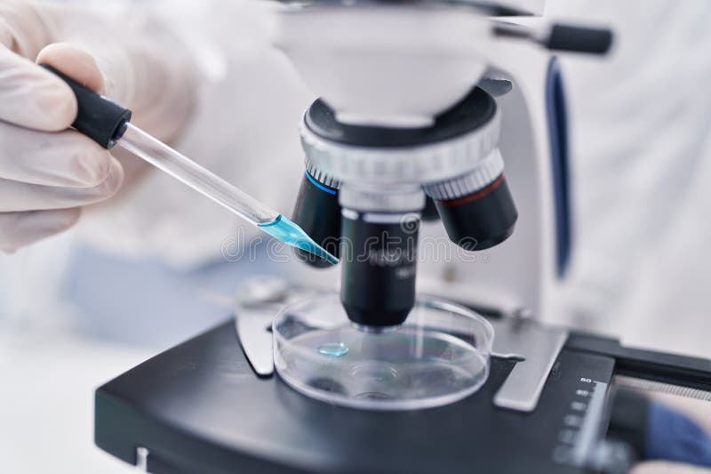 Young Hispanic Man Scientist Pouring Liquid on Sample Using Microscope ...
