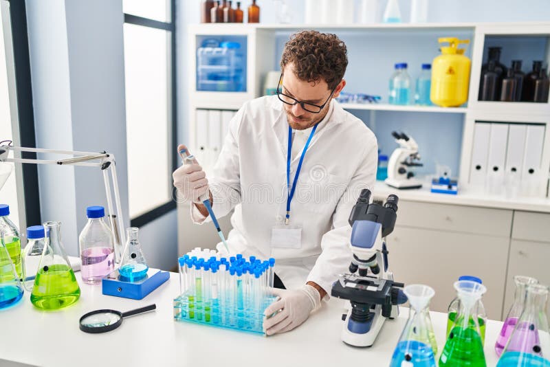 Young Hispanic Man Scientist Pouring Liquid on Test Tubes at Laboratory ...