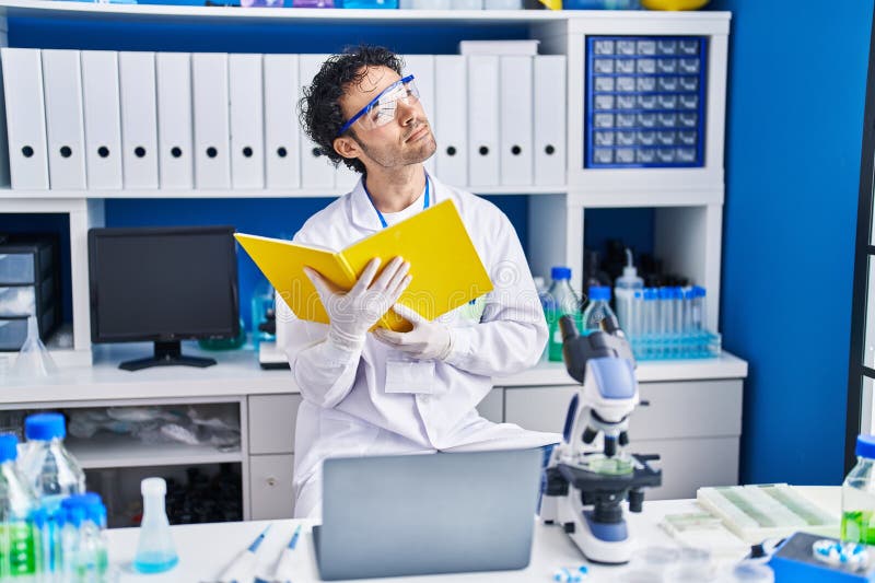 Young Hispanic Man Scientist Reading Book at Laboratory Stock Photo ...