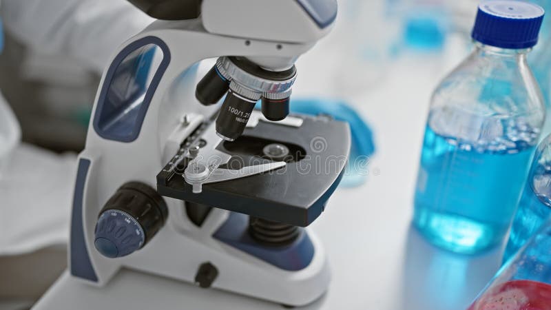 Young Hispanic Man Scientist Using Microscope at Laboratory Stock Photo ...