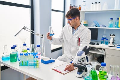 Young Hispanic Man Scientist Weighing Liquid Writing on Document at ...