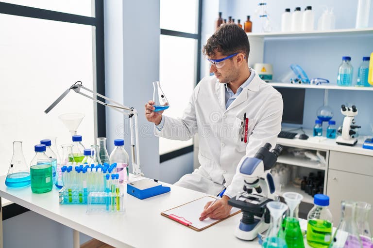 Young Hispanic Man Scientist Weighing Liquid Writing on Document at ...