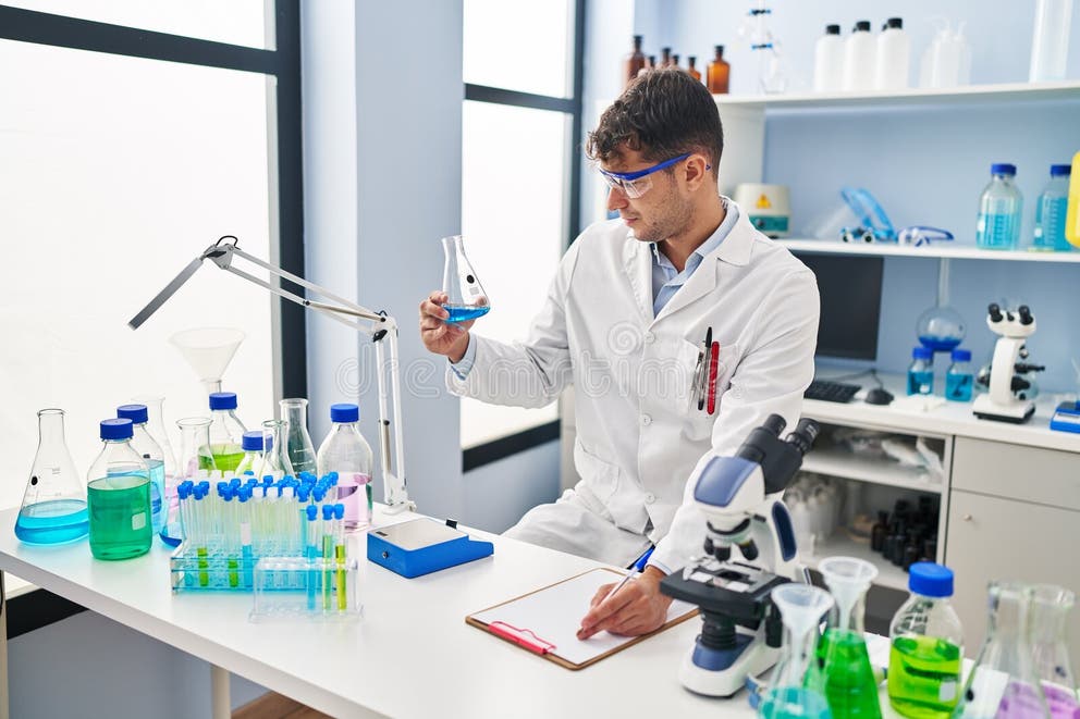Young Hispanic Man Scientist Weighing Liquid Writing on Document at ...