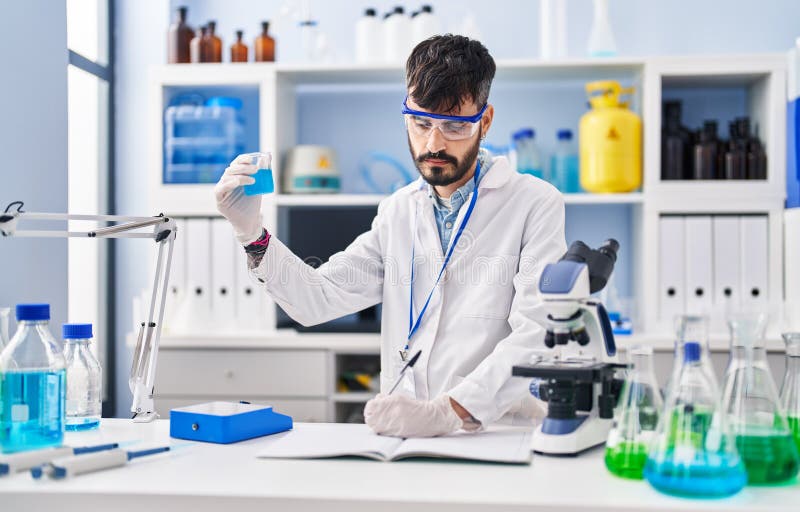 Young Hispanic Man Scientist Writing on Notebook Measuring Liquid at ...