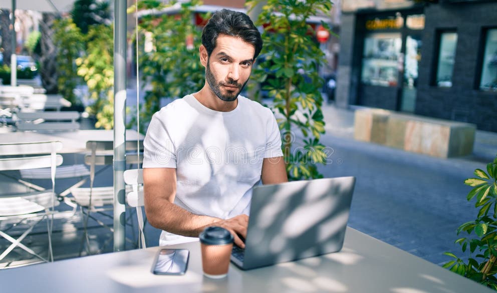 Young Hispanic Man with Serious Expression Working Using Laptop at ...