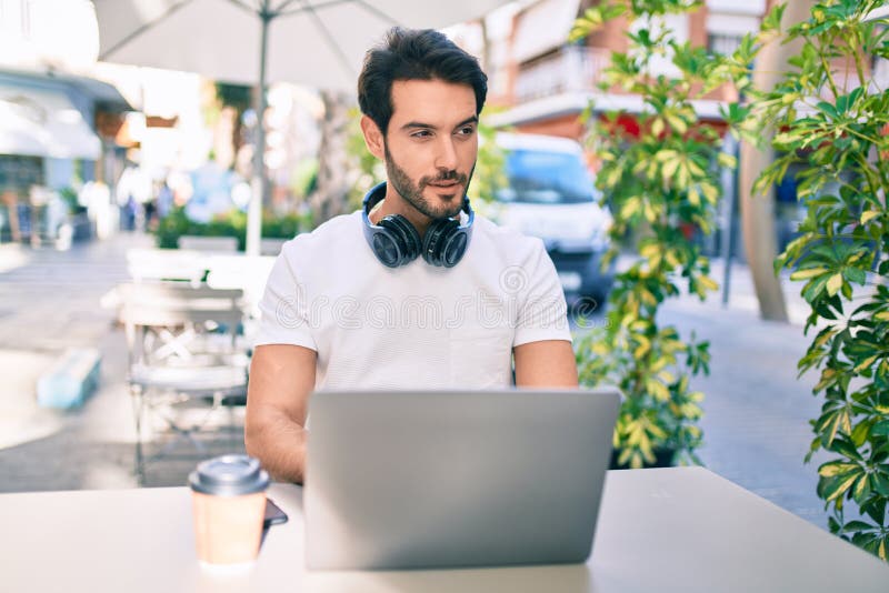 Young Hispanic Man with Serious Expression Working Using Laptop at ...