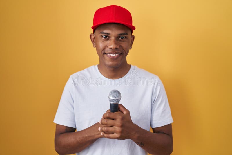 Young Hispanic Man Singing Song Using Microphone Smiling with a Happy ...