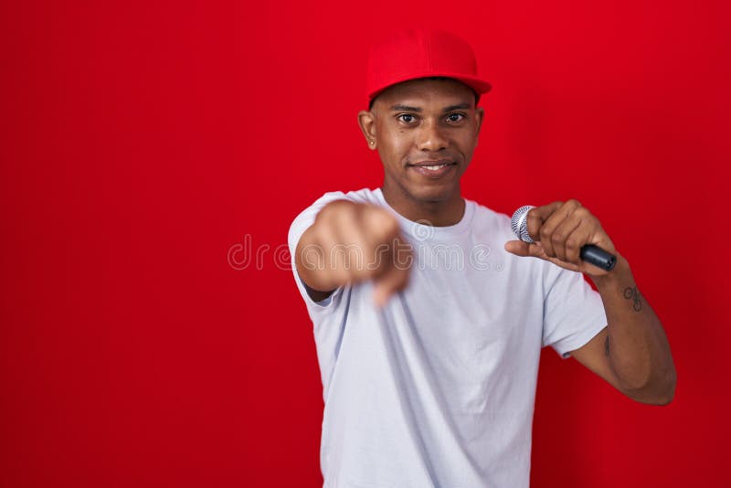 Young Hispanic Man Singing Song Using Microphone Smiling Happy Pointing ...