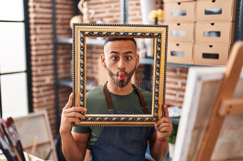 Young Hispanic Man Sitting at Art Studio with Empty Frame Making Fish ...