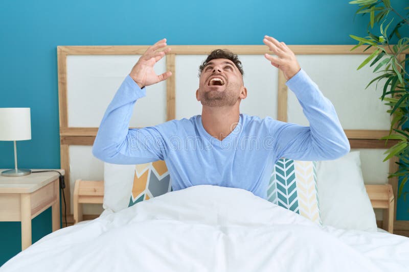 Young Hispanic Man Sitting on Bed Screaming at Bedroom Stock Image ...