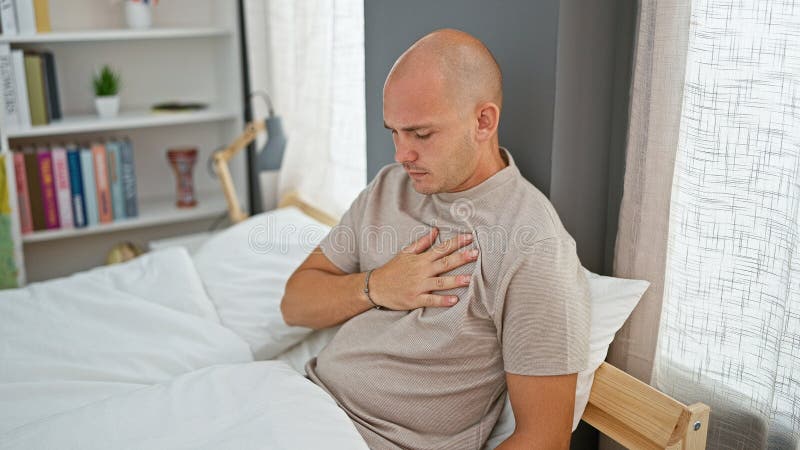 Young Hispanic Man Sitting on Bed Suffering Heart Attack at Bedroom ...