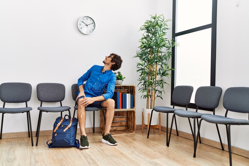 Young Hispanic Man Sitting on Chair Looking Clock at Waiting Room Stock ...