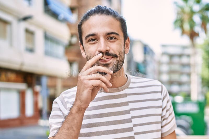 Young Hispanic Man Smiling Confident Smoking Cigarette at Street Stock ...