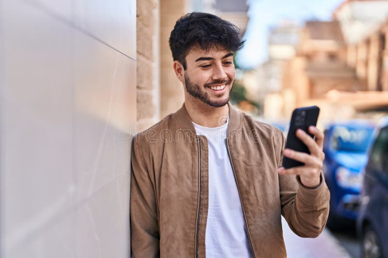 Young Hispanic Man Smiling Confident Using Smartphone at Street Stock ...