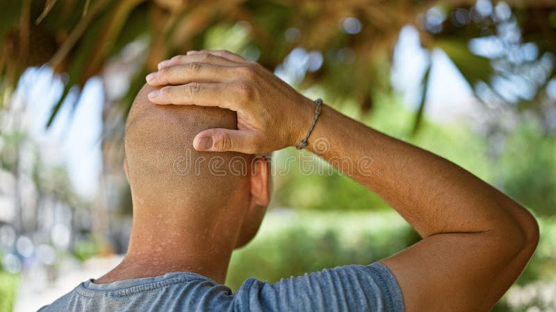 Young Hispanic Man Standing Backwards Touching Head at Park Stock Photo ...