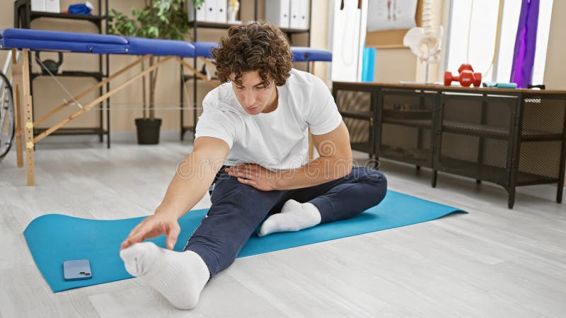 Young Hispanic Man Stretching in a Rehabilitation Clinic Interior Stock ...