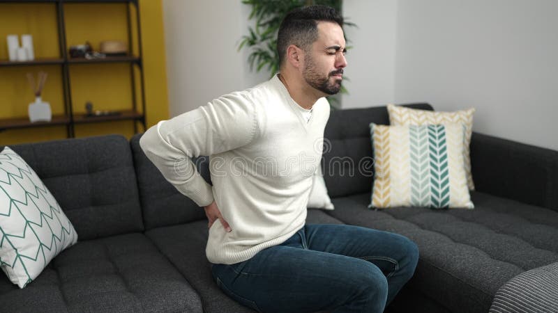 Young Hispanic Man Suffering for Backache Sitting on Sofa at Home Stock ...