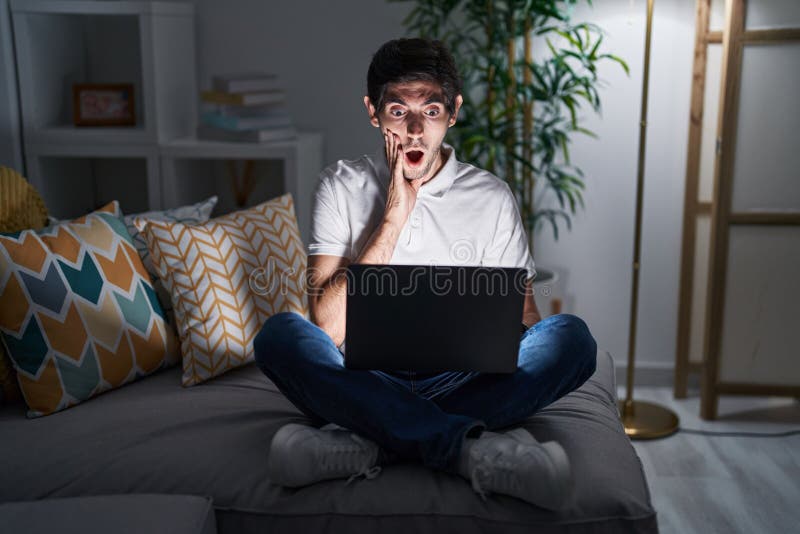 Young Hispanic Man Using Laptop at Home at Night Afraid and Shocked ...
