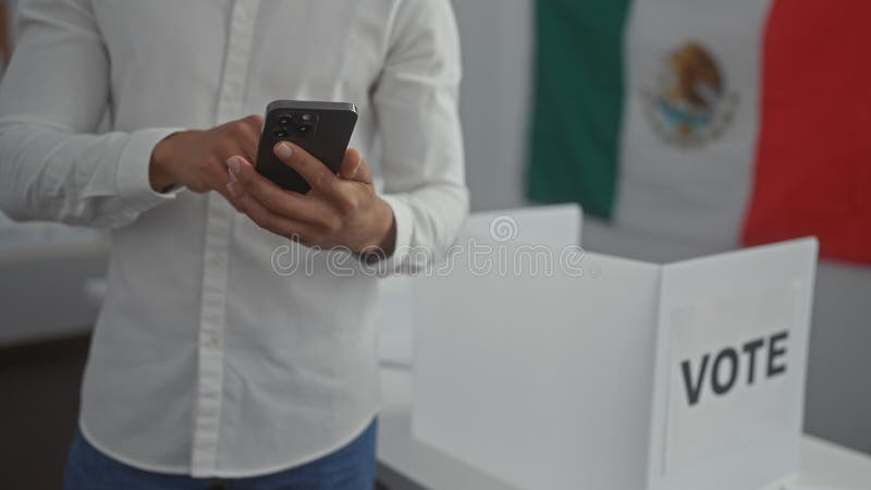 Young Hispanic Man Using Smartphone in Mexican Voting Room with Flag ...