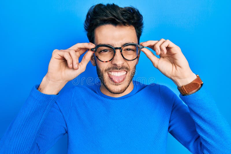 Young Hispanic Man Wearing Glasses Sticking Tongue Out Happy With Funny