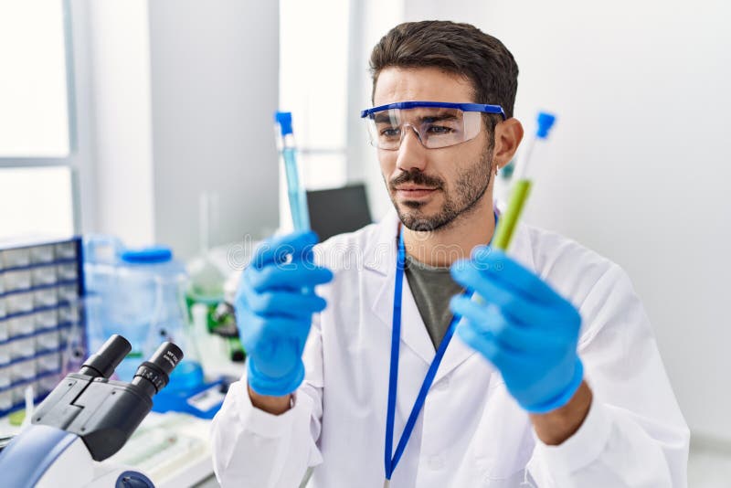 Young Hispanic Man Wearing Scientist Uniform Holding Test Tubes at ...