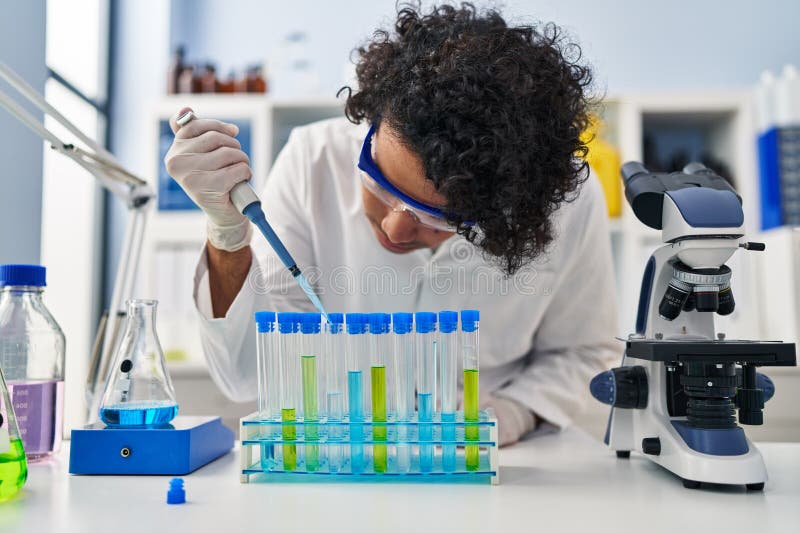 Young Hispanic Man Wearing Scientist Uniform Using Pipette at ...