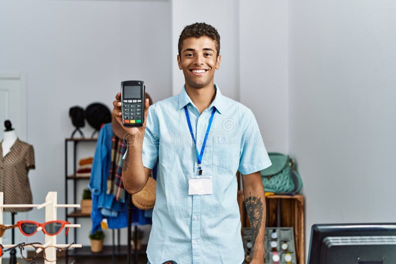 Young Hispanic Man Working As Shop Assistant Holding Dataphone at ...