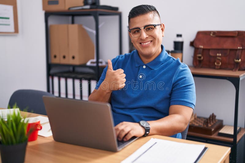 Young Hispanic Man Working at the Office with Laptop Doing Happy Thumbs ...