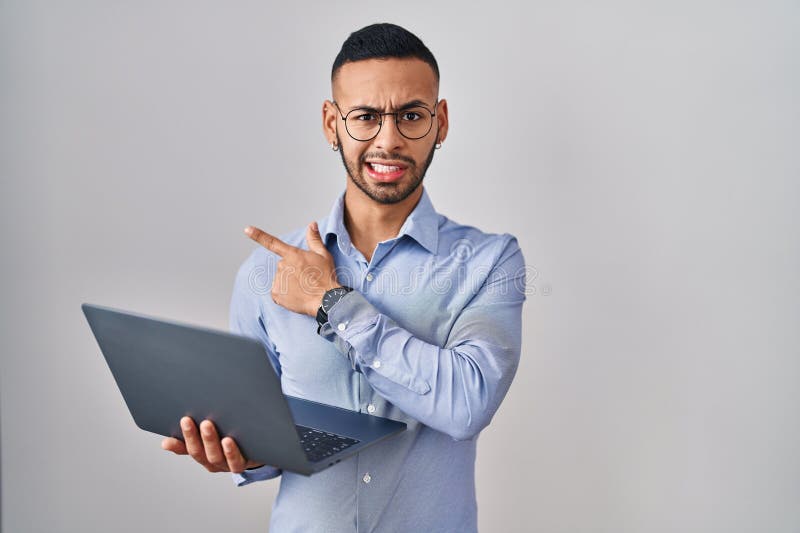 Young Hispanic Man Working Using Computer Laptop Pointing Aside Worried ...