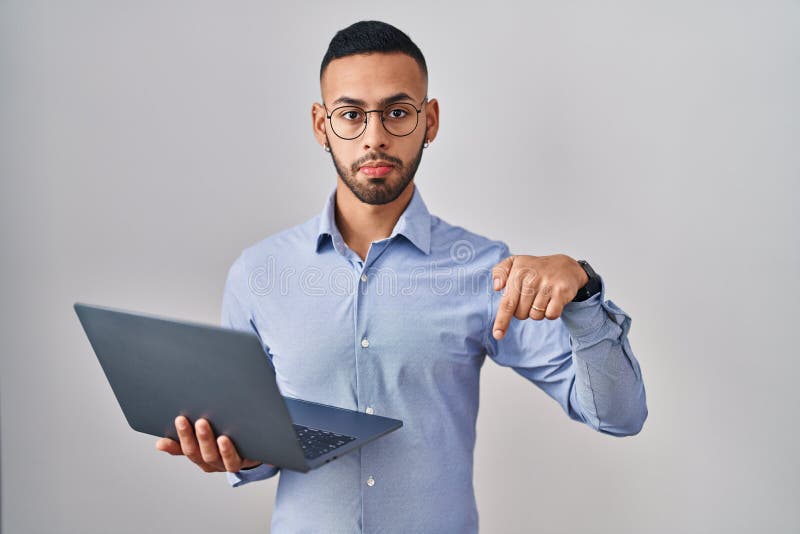 Young Hispanic Man Working Using Computer Laptop Pointing Down Looking ...