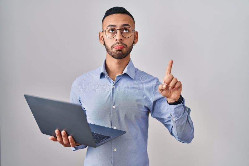Young Hispanic Man Working Using Computer Laptop Pointing Up Looking ...