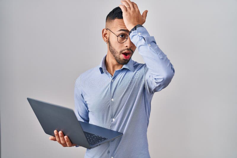 Young Hispanic Man Working Using Computer Laptop Surprised with Hand on ...