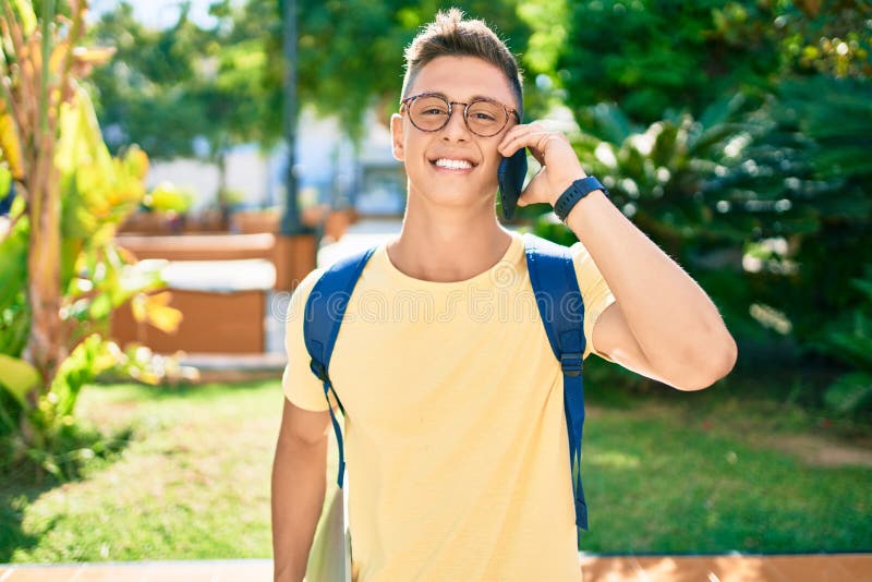 Young Hispanic Student Smiling Happy Using Smartphone Walking the ...