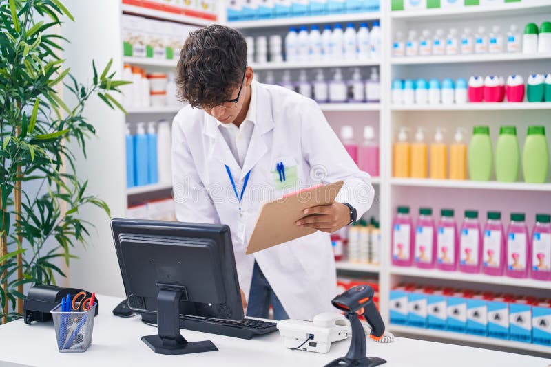 Young Hispanic Teenager Pharmacist Using Computer Reading Document at ...