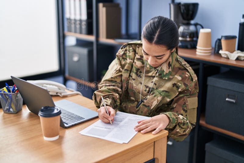 Young Hispanic Woman Army Soldier Using Laptop Writing on Document at ...
