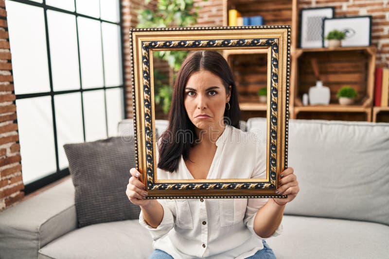 Young Hispanic Woman Holding Empty Frame Depressed and Worry for ...