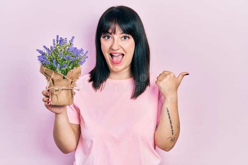 Young Hispanic Woman Holding Lavender Plant Pointing Thumb Up To The