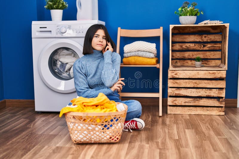 Young Hispanic Woman at Laundry Room Serious Face Thinking about ...