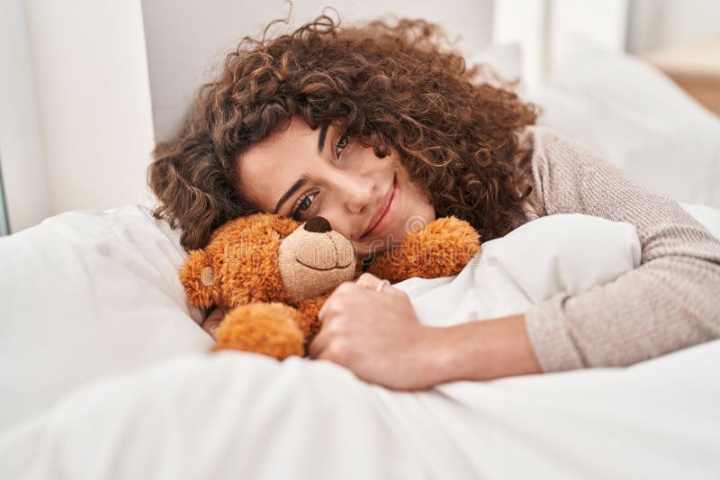 Young Hispanic Woman Lying on Bed Hugging Teddy Bear at Bedroom Stock ...