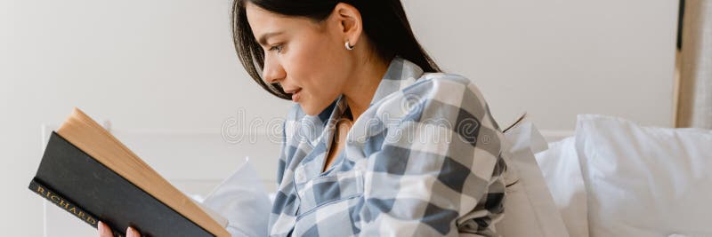 Young Hispanic Woman Reading Book while Lying at Home Stock Photo ...