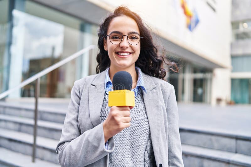 Young Hispanic Woman Reporter Working Using Microphone at Street Stock ...